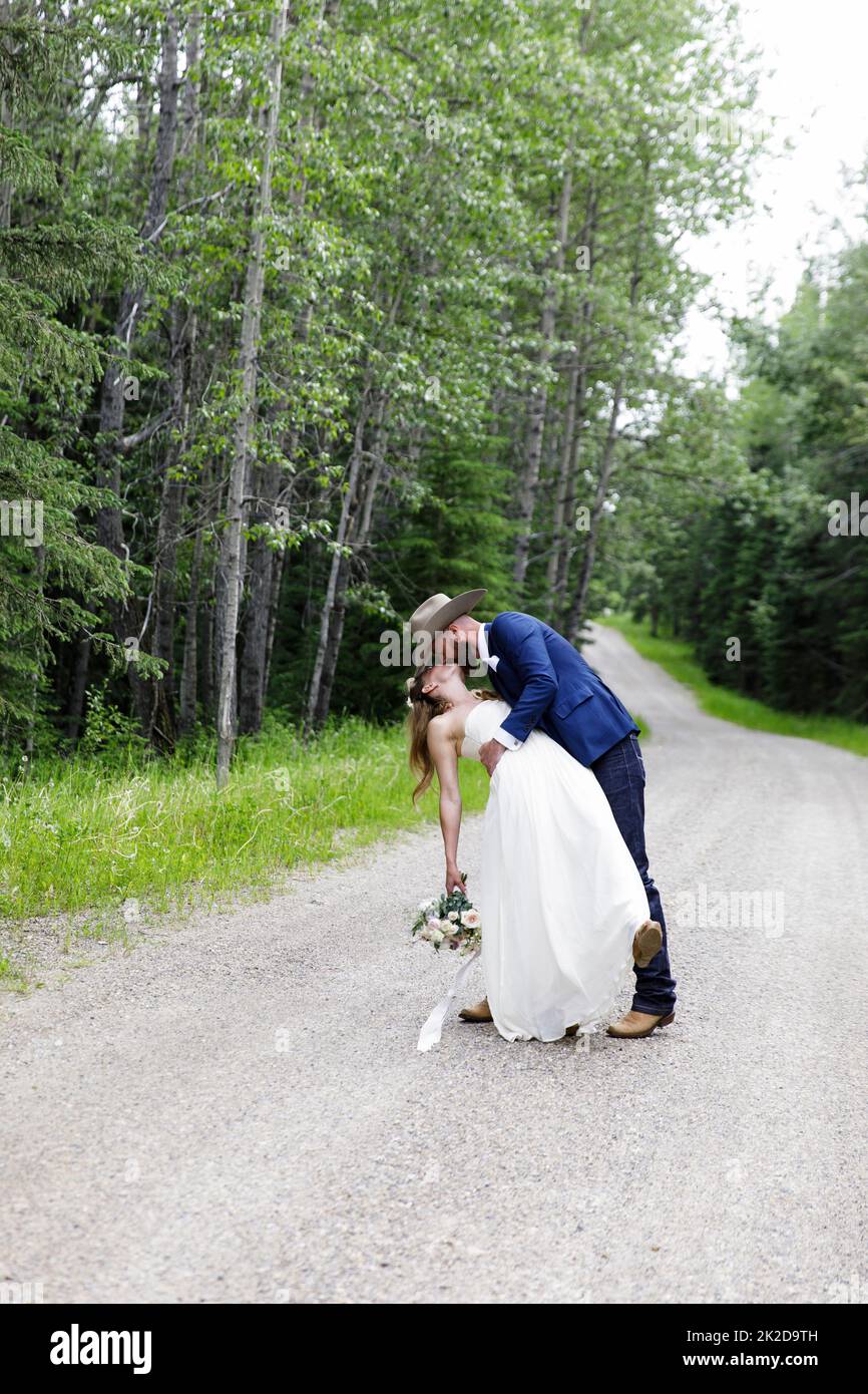 Affectionate bride and groom kissing on rural gravel road Stock Photo ...