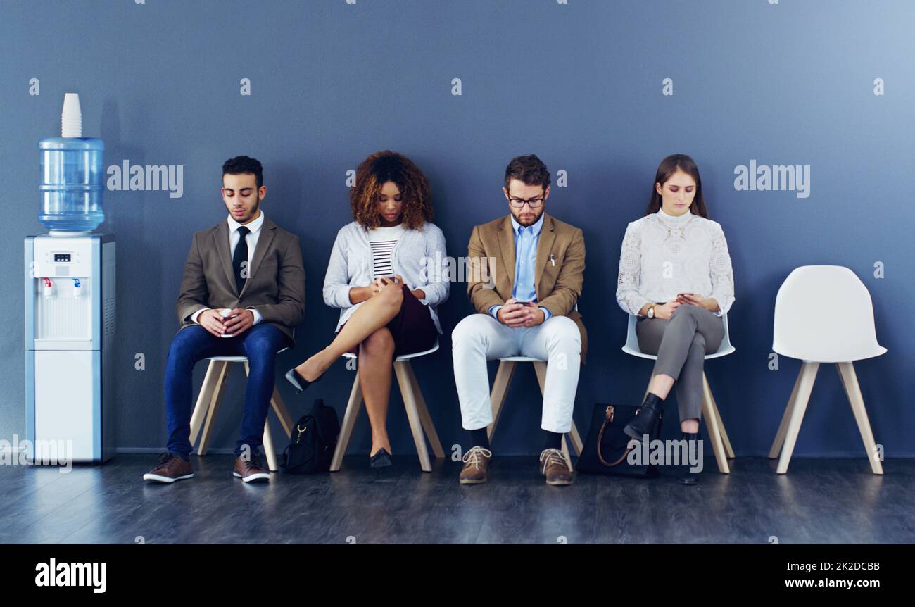 Its D-Day. Full length shot of four businesspeople sitting in line for ...