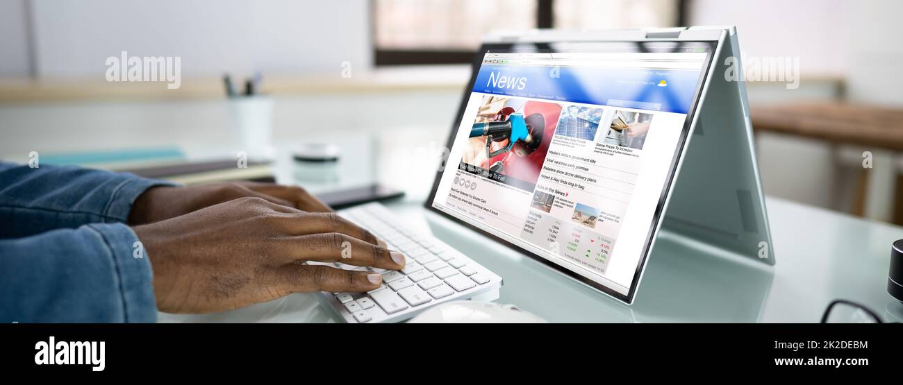 Reading Newspaper Article On Laptop Stock Photo - Alamy