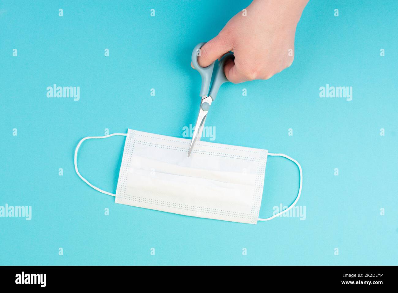 Covid-19 mask cut into two pieces with a scissor, end of pandemic, back ...