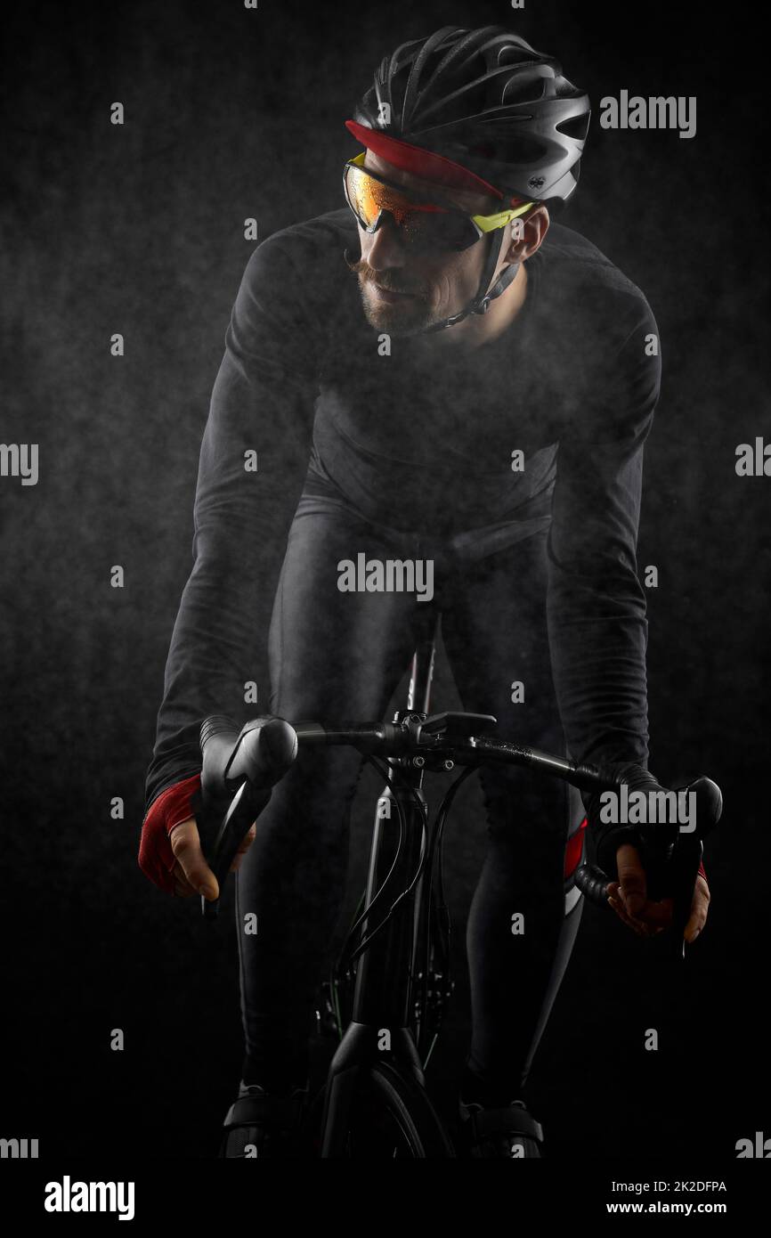 male cyclist riding road bicycle on black background Stock Photo - Alamy