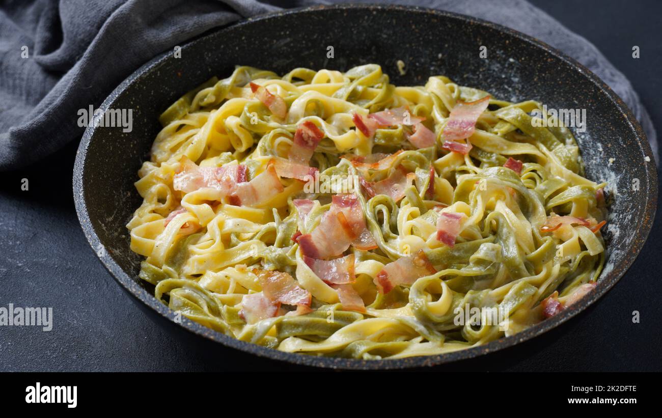 Italian egg pasta carbonara in black pan with bacon, parmesan cheese ...