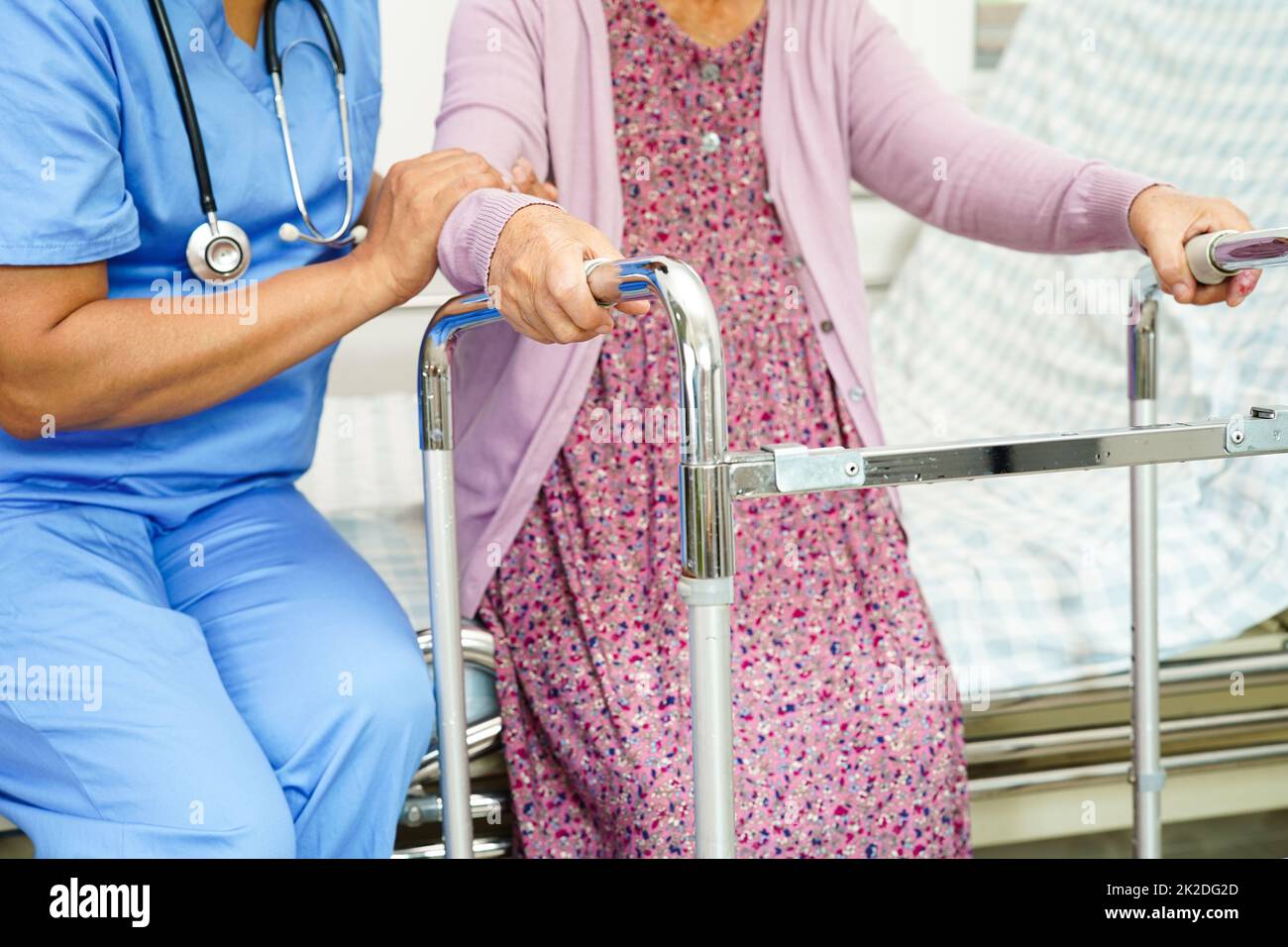 Caregiver help Asian elderly woman disability patient walk with walker in nursing hospital ...