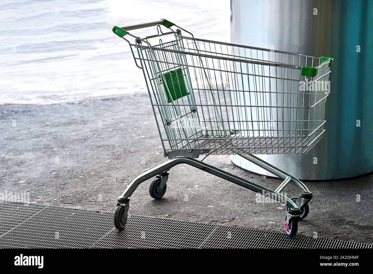 An empty shopping cart stands in front of the entrance to the shopping ...