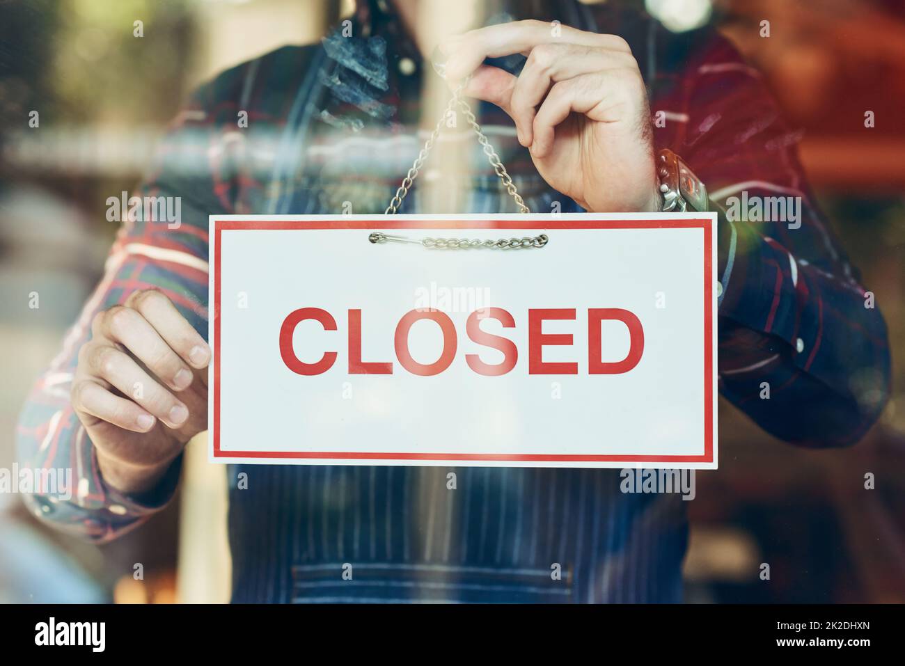 Closing up shop for the day. Closeup shot of a young man hanging up a ...