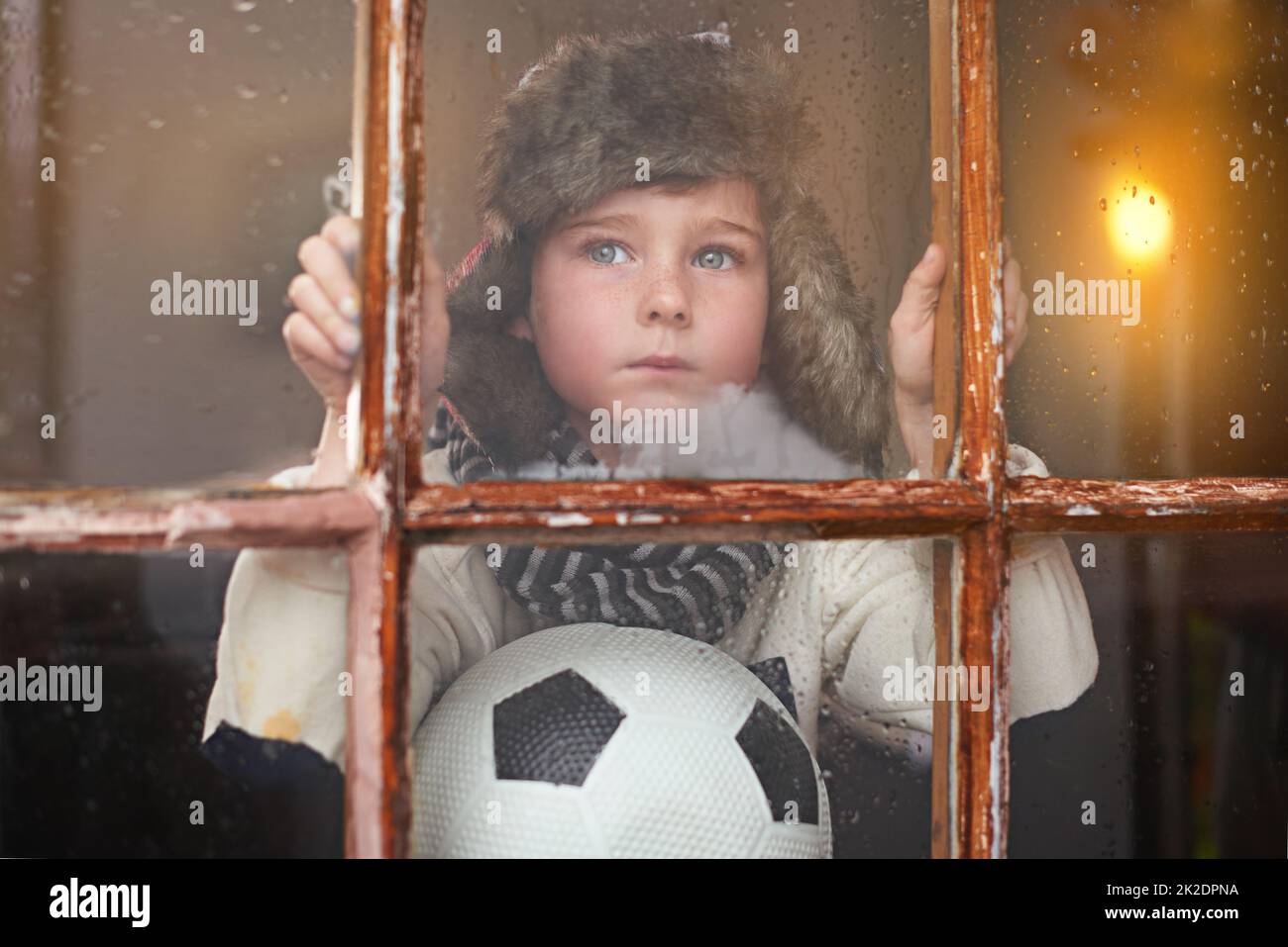 Looks like the rain is clearing up. A young boy sitting by the window ...