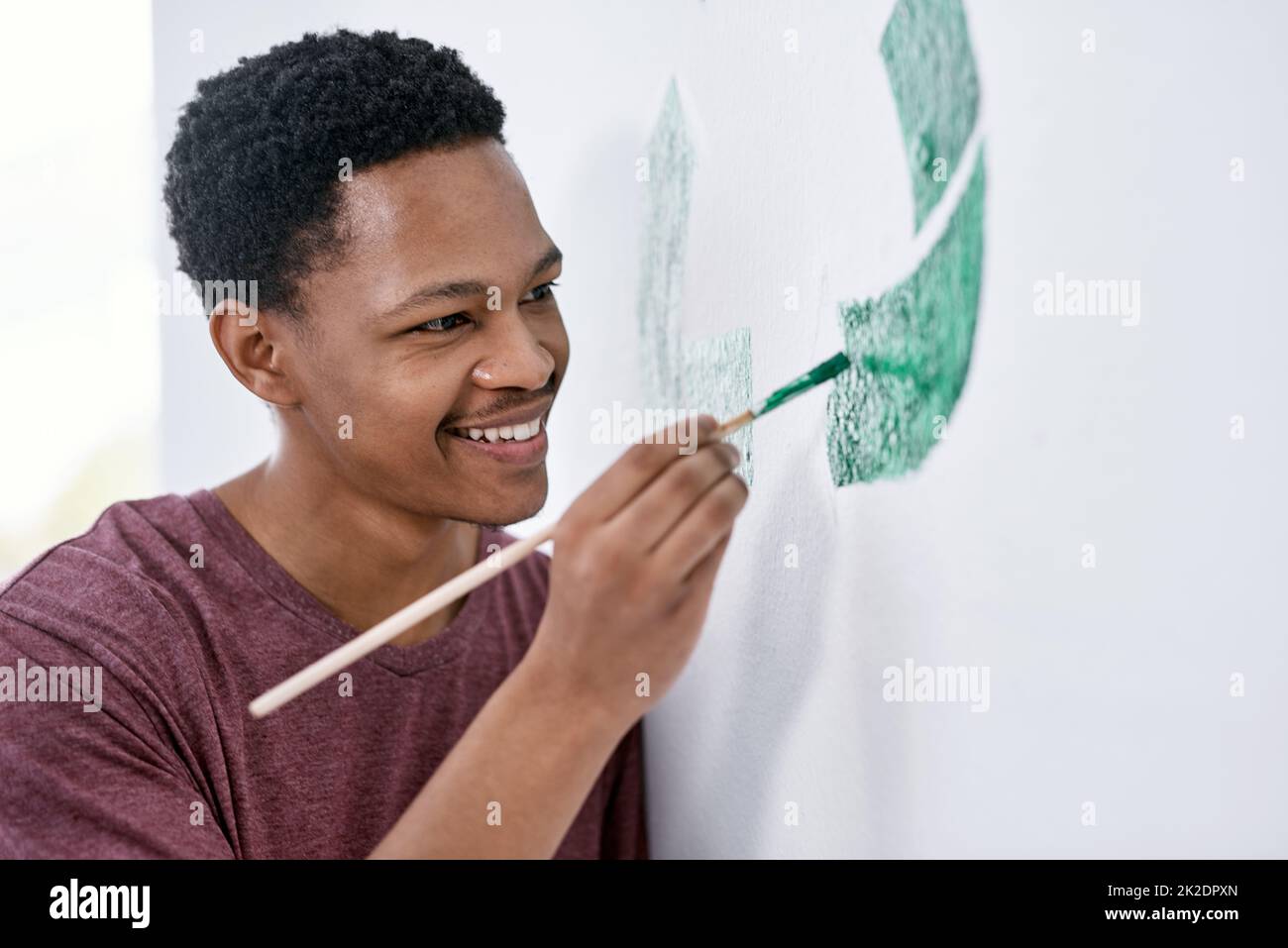 The green life is the good life. Shot of a young man painting a recycle ...