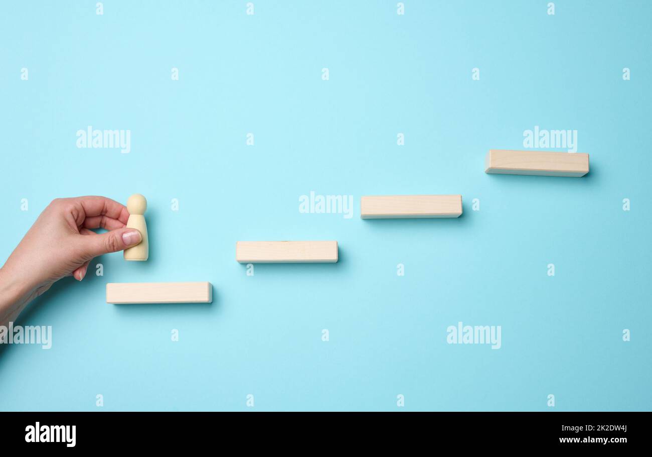wooden steps and a figurine of a little man in a woman's hand. Startup ...