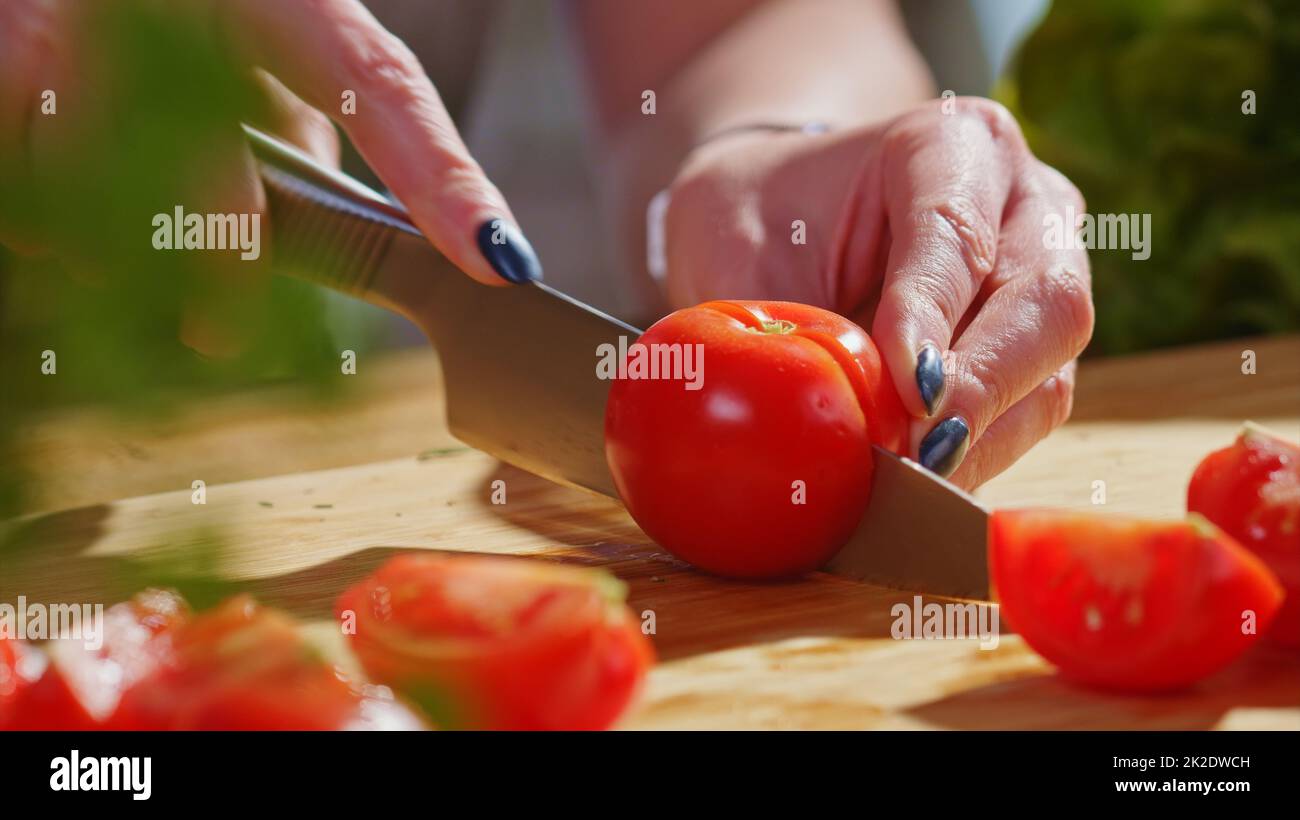 Woman slicing tomato for cooking in kitchen Stock Photo - Alamy