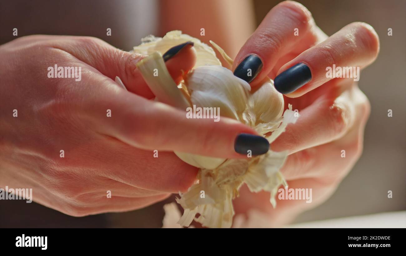 Woman peeling garlic for cooking in kitchen Stock Photo - Alamy