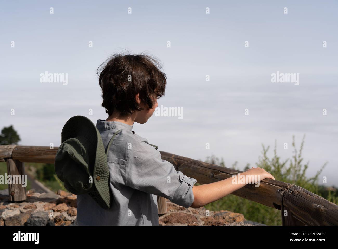 A teenager stands on an observation deck high in the mountains and ...