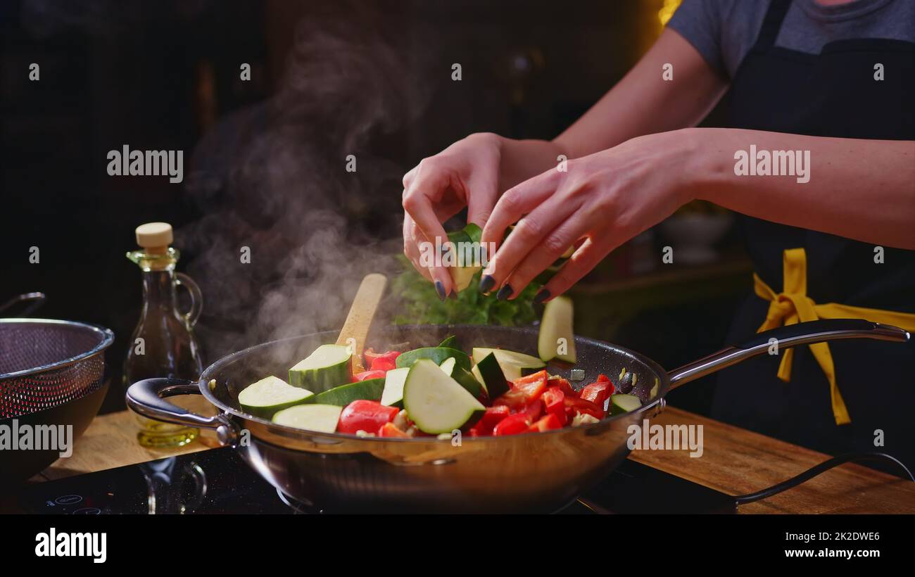 Woman cooking frying in kitchen in wok pan Stock Photo - Alamy