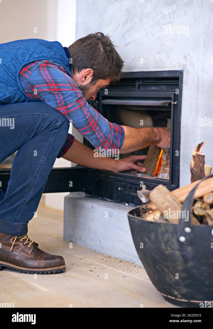 Ready for the winter. a young man building a fire in his fireplace at ...