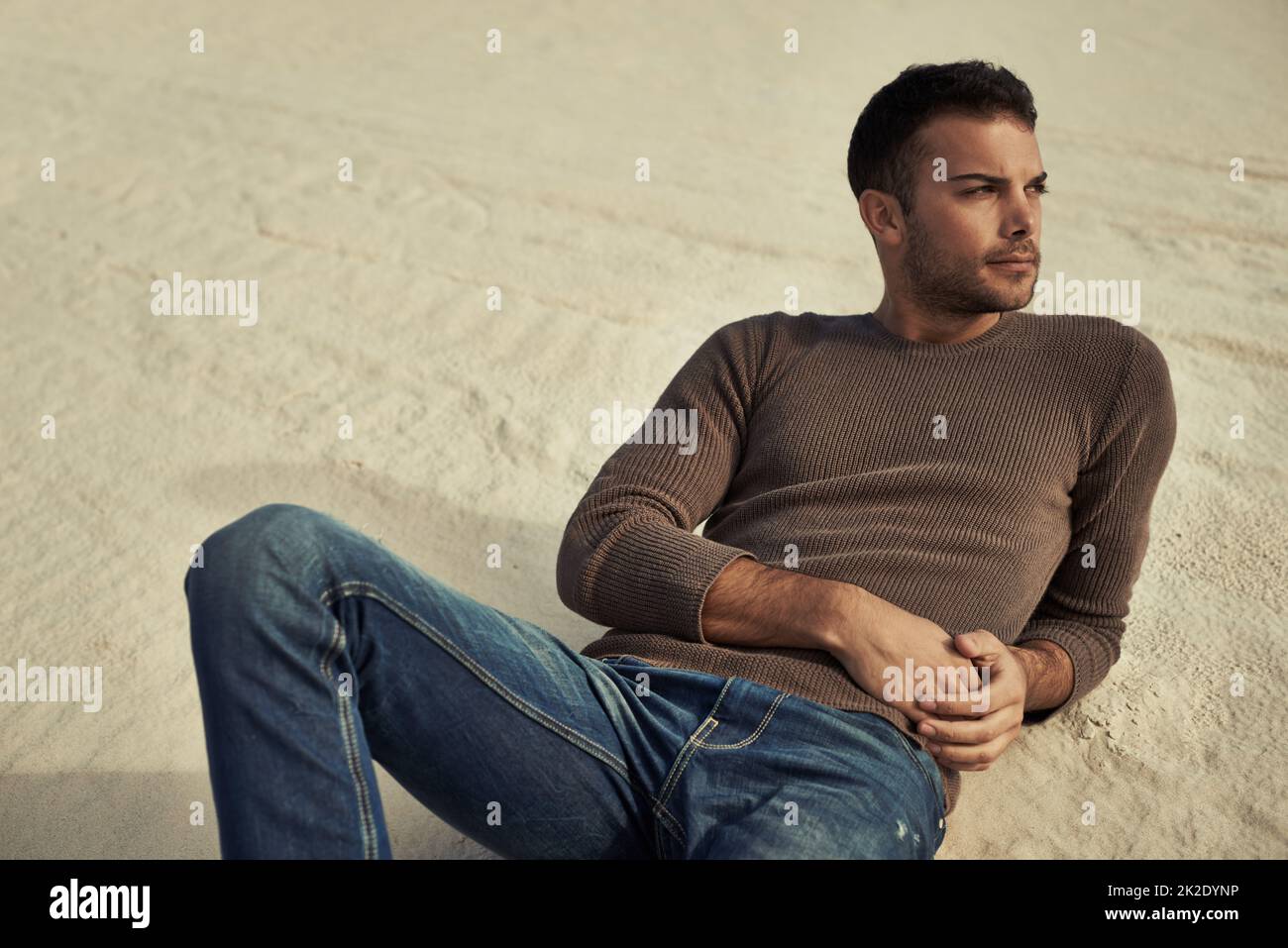 Looking stylish in the desert. A handsome male model reclining on the ...
