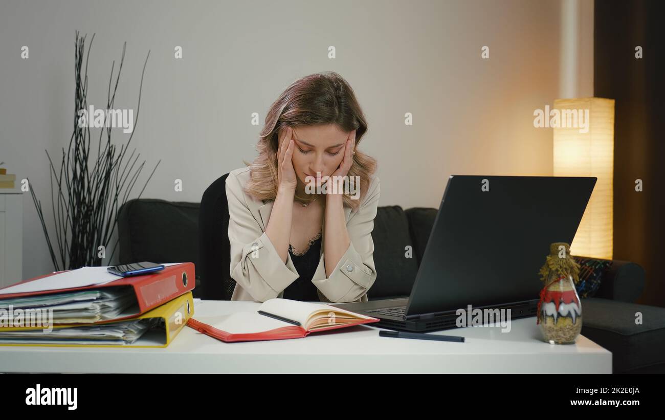 Tired woman, overwhelmed by laptop work, has severe headache Stock ...