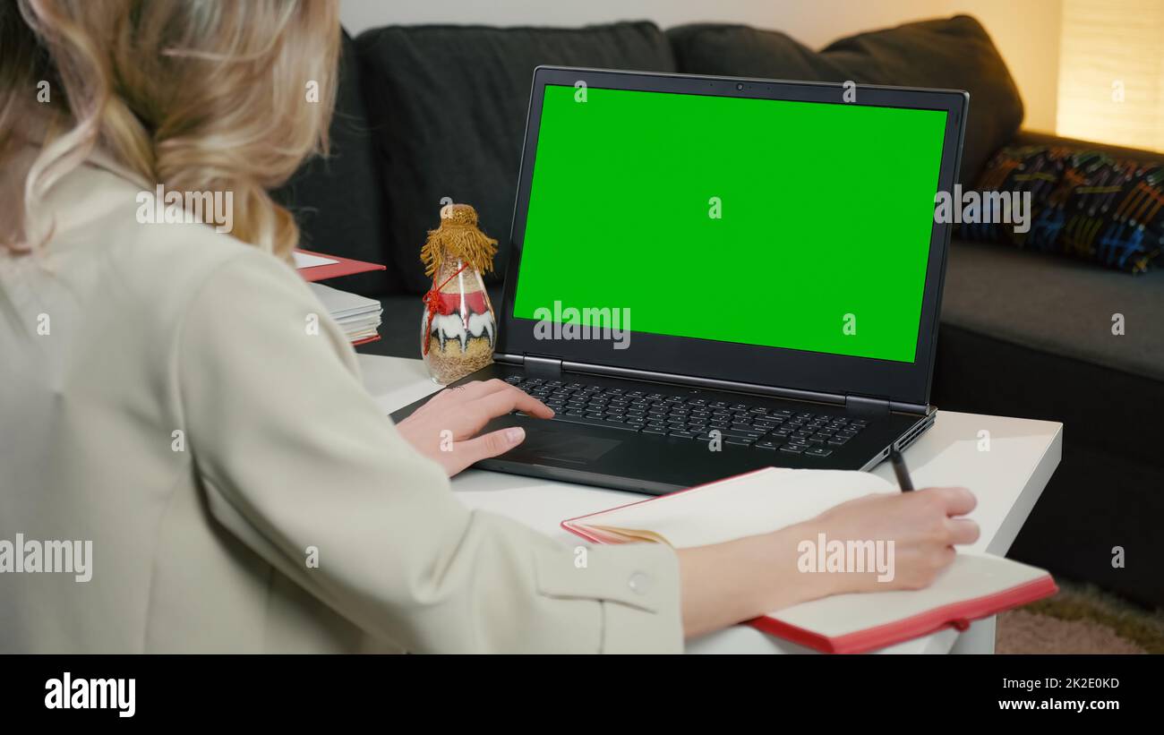 Chromakey Mockup. Woman writing and using laptop with blank green ...