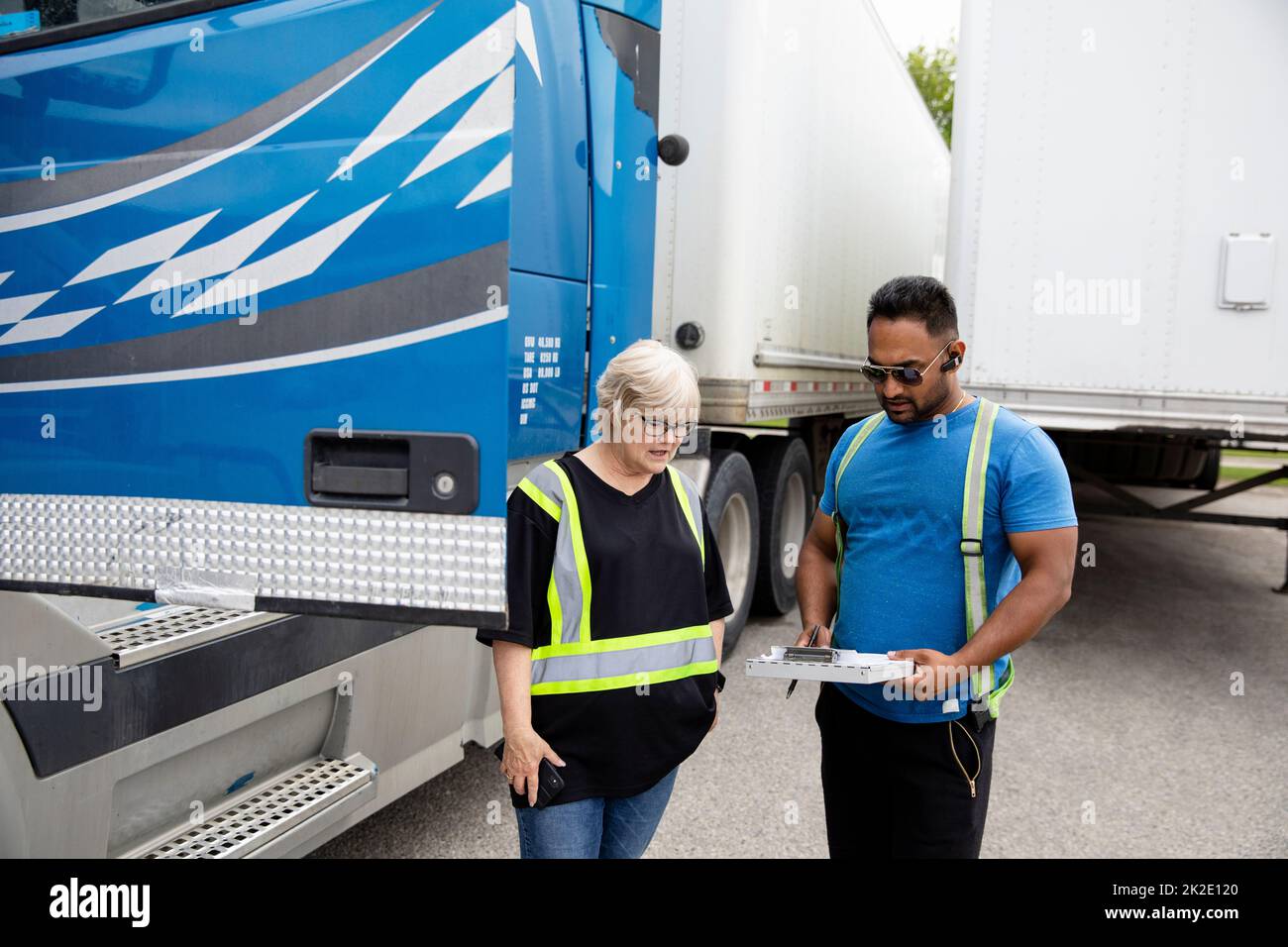 Trucker and warehouse owner checking paperwork for container semi truck ...