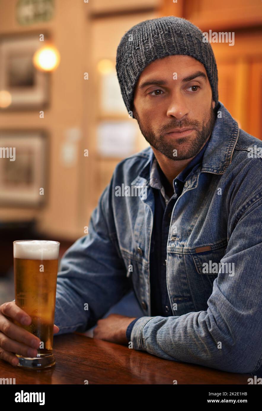 Is it beer thirty yet. a handsome young man drinking a beer at the bar ...