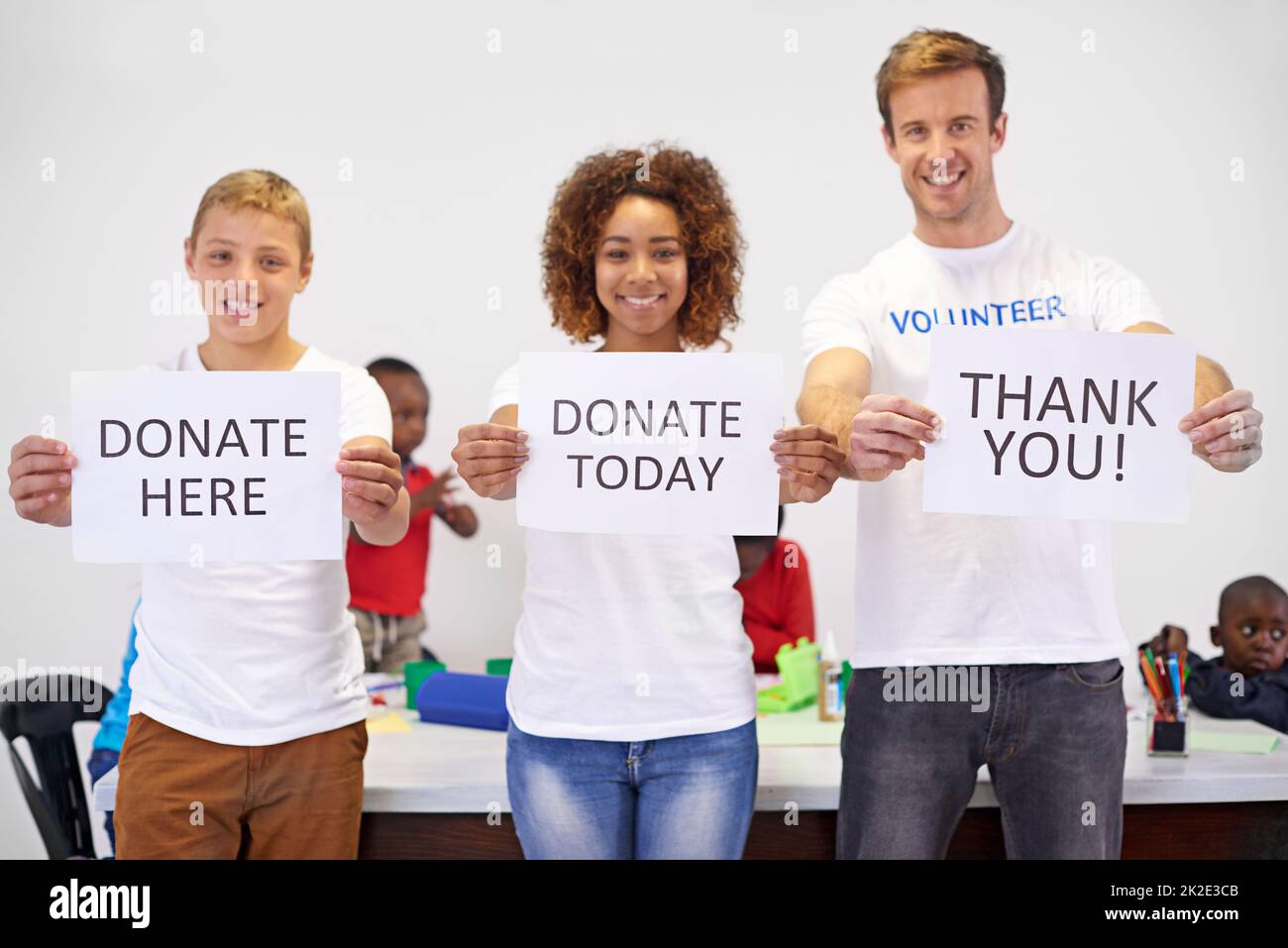 Help today. Portrait of volunteers holding up signs while working with ...