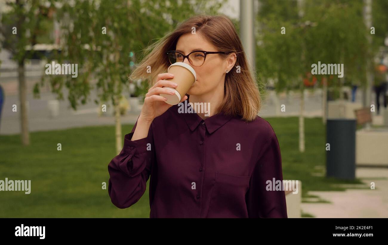 Young blonde Woman walking out of office building and drink coffee ...
