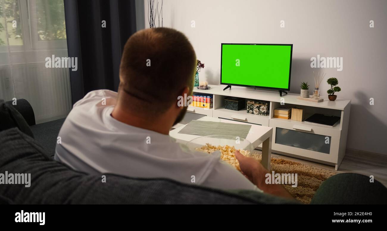 Man Watching Television with Green Screen Chroma Key, shot behind models shoulders. Man Eating ...