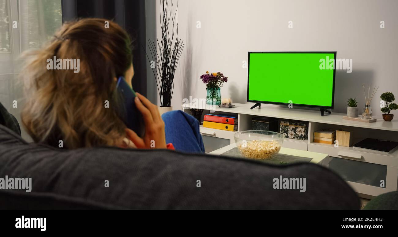 Woman watching Tv Green Chroma Key Screen and talking on Phone. Young ...