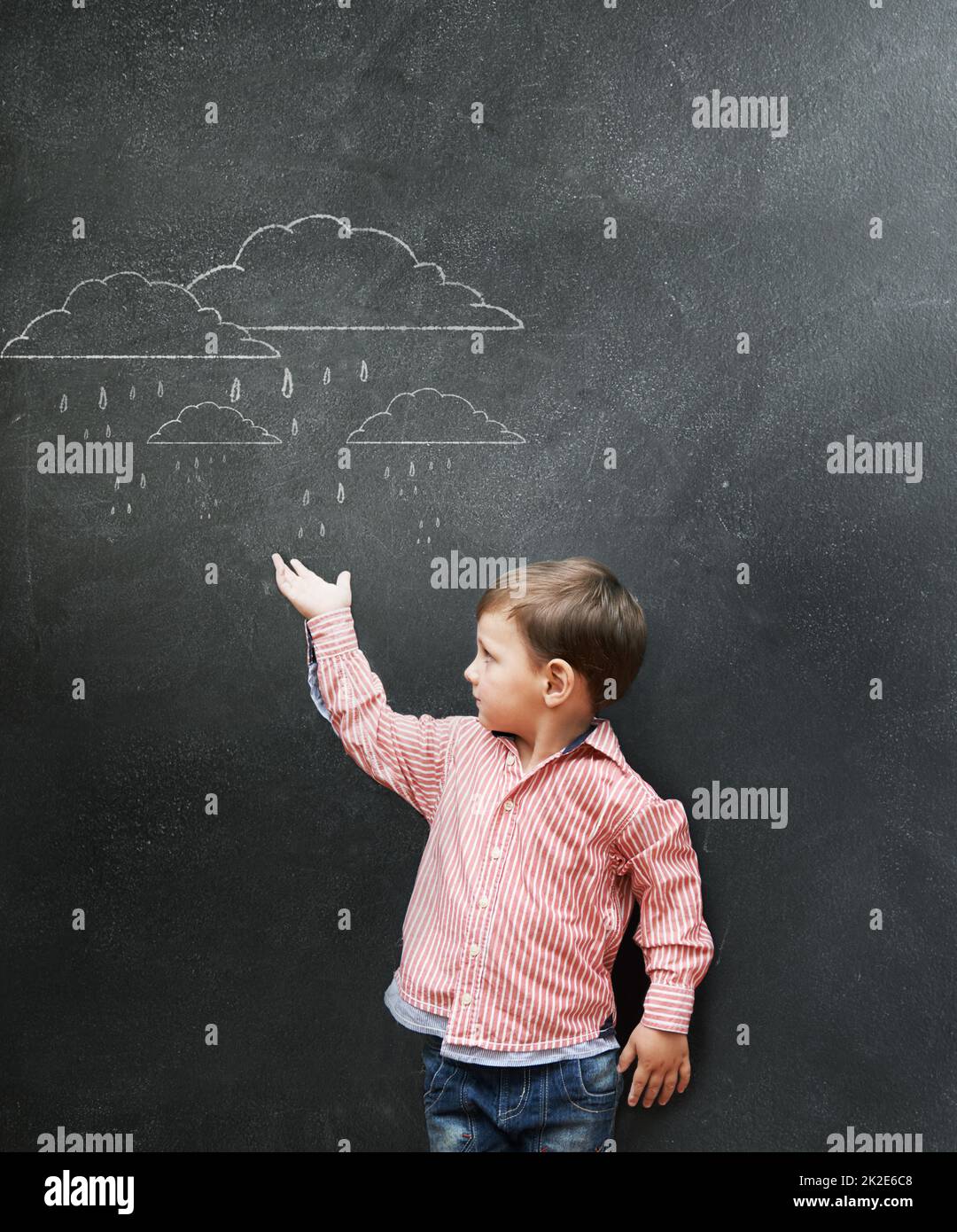 Weather man of the future. A young boy showing drawings of rain clouds ...