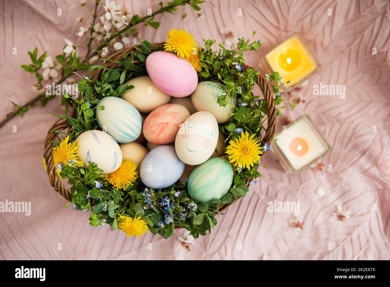 On a pastel bedspread is a basket of grass and bright flowers. The ...