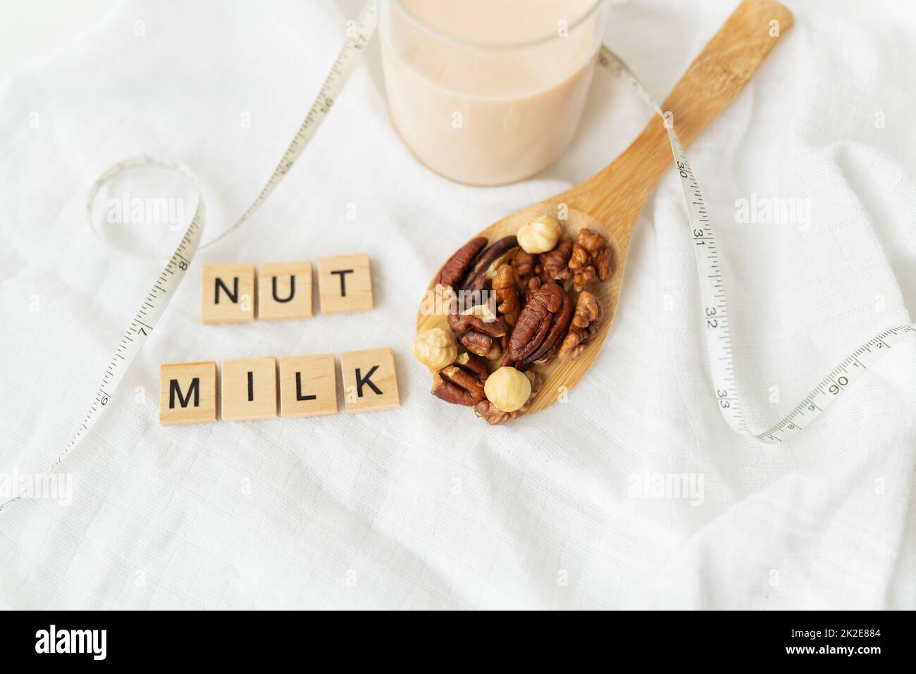 Vegan milk from nuts in a glass cup with various nuts on a white table ...