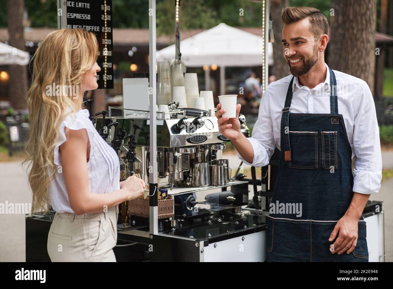 Barista man giving cup of coffee to woman customer Stock Photo - Alamy