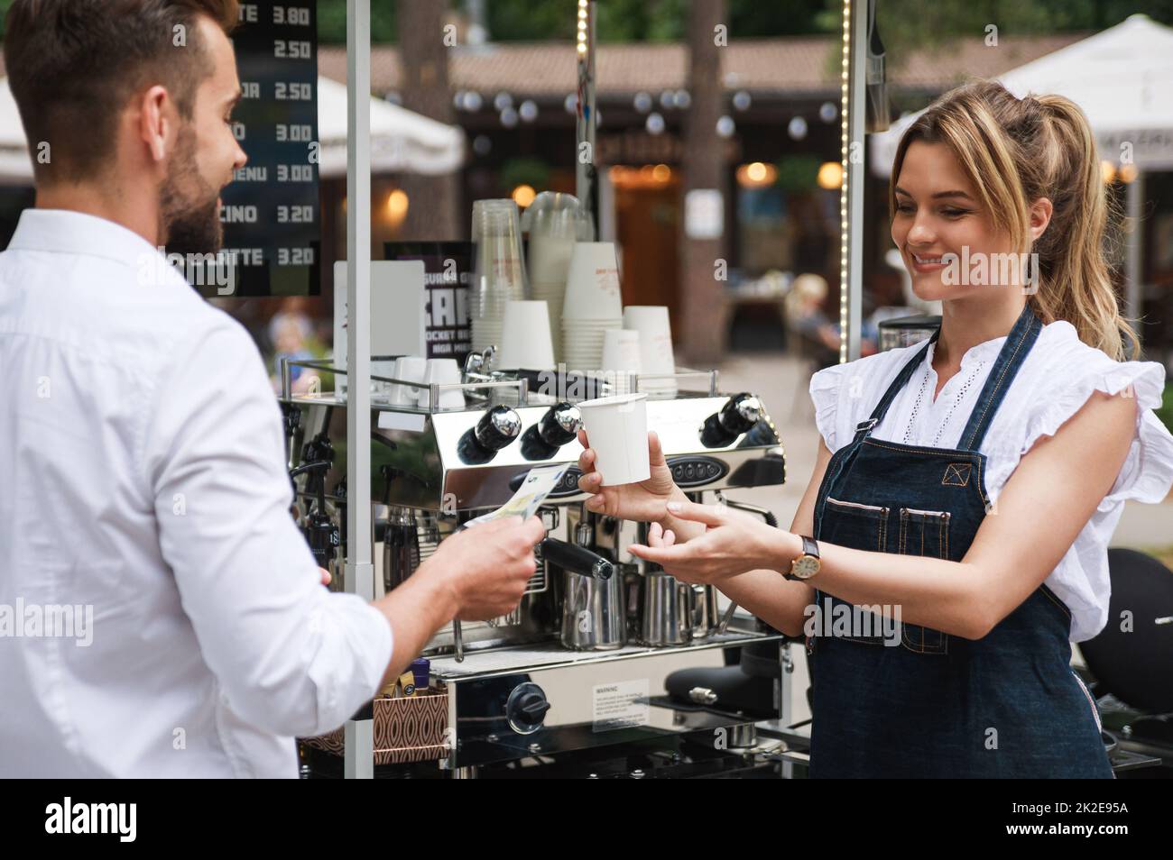 Beautiful woman barista selling coffee to the customer Stock Photo - Alamy
