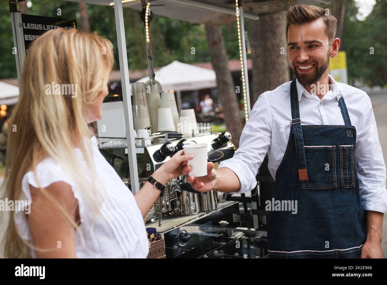 Barista man giving cup of coffee to woman customer Stock Photo - Alamy