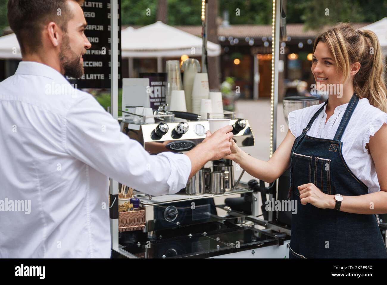Beautiful woman barista selling coffee to the customer Stock Photo - Alamy
