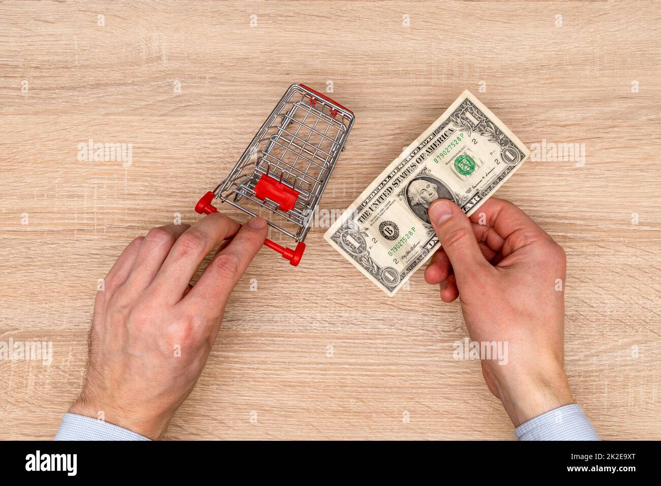 Businessman pushes the toy cart and holds one dollar bill in the hand ...