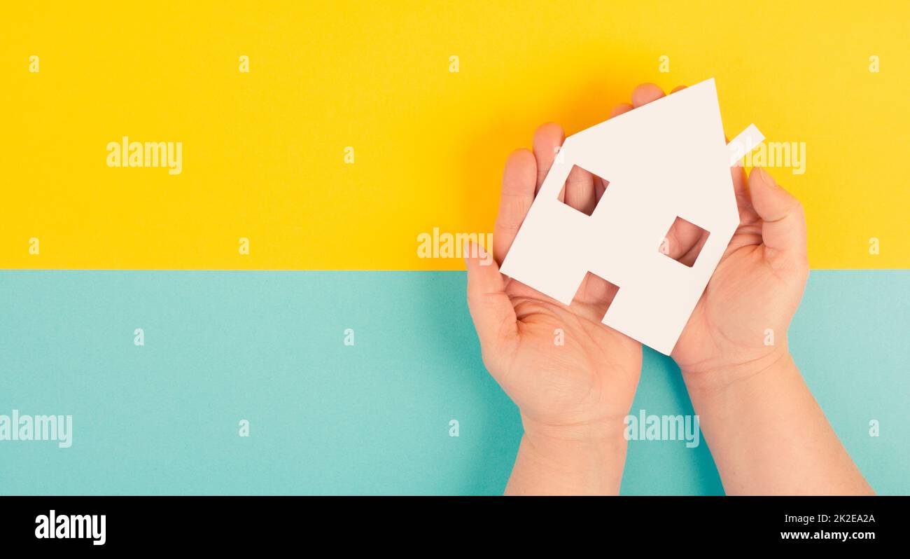 Holding a small paper house in the hands, planning to buy a new home ...