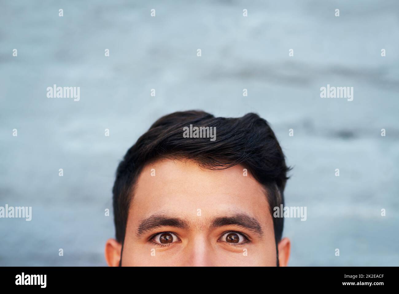 Look into my eyes. Cropped portrait of a young mans face peeking from ...