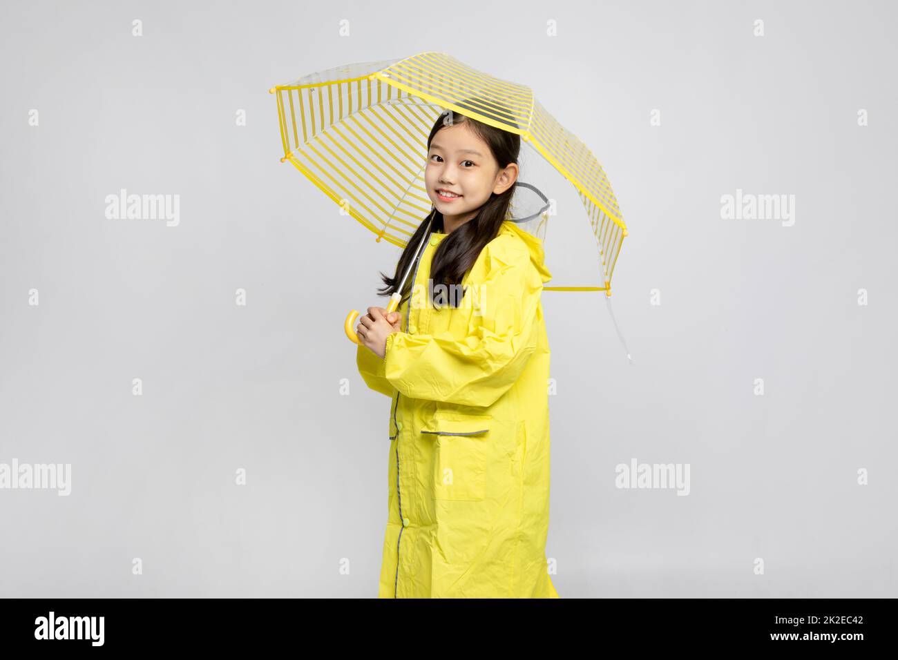 cute young Korean girl, rainy season concept in white background studio wearing raincoat and ...