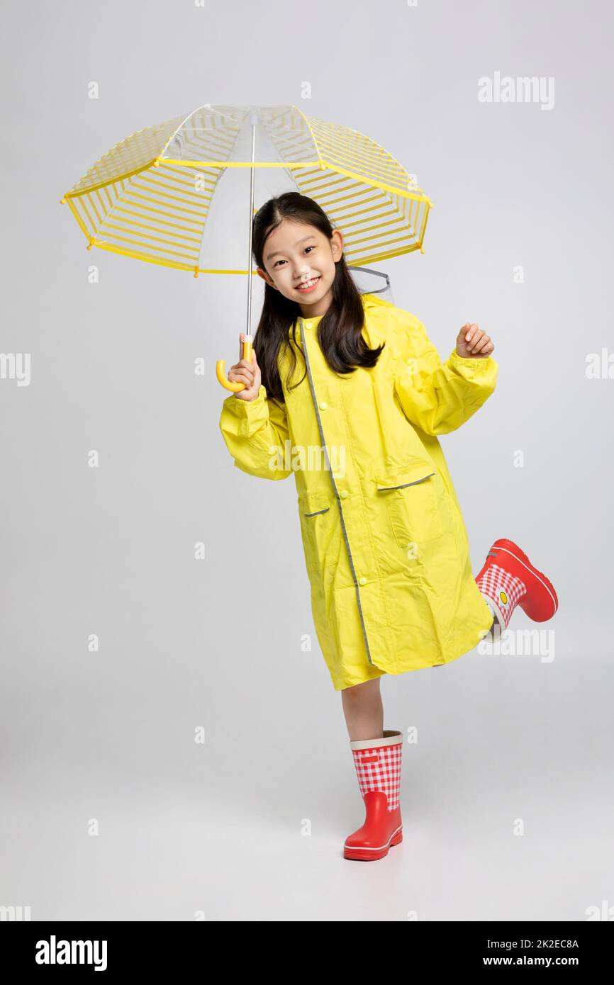cute young Korean girl, rainy season concept in white background studio wearing raincoat and ...