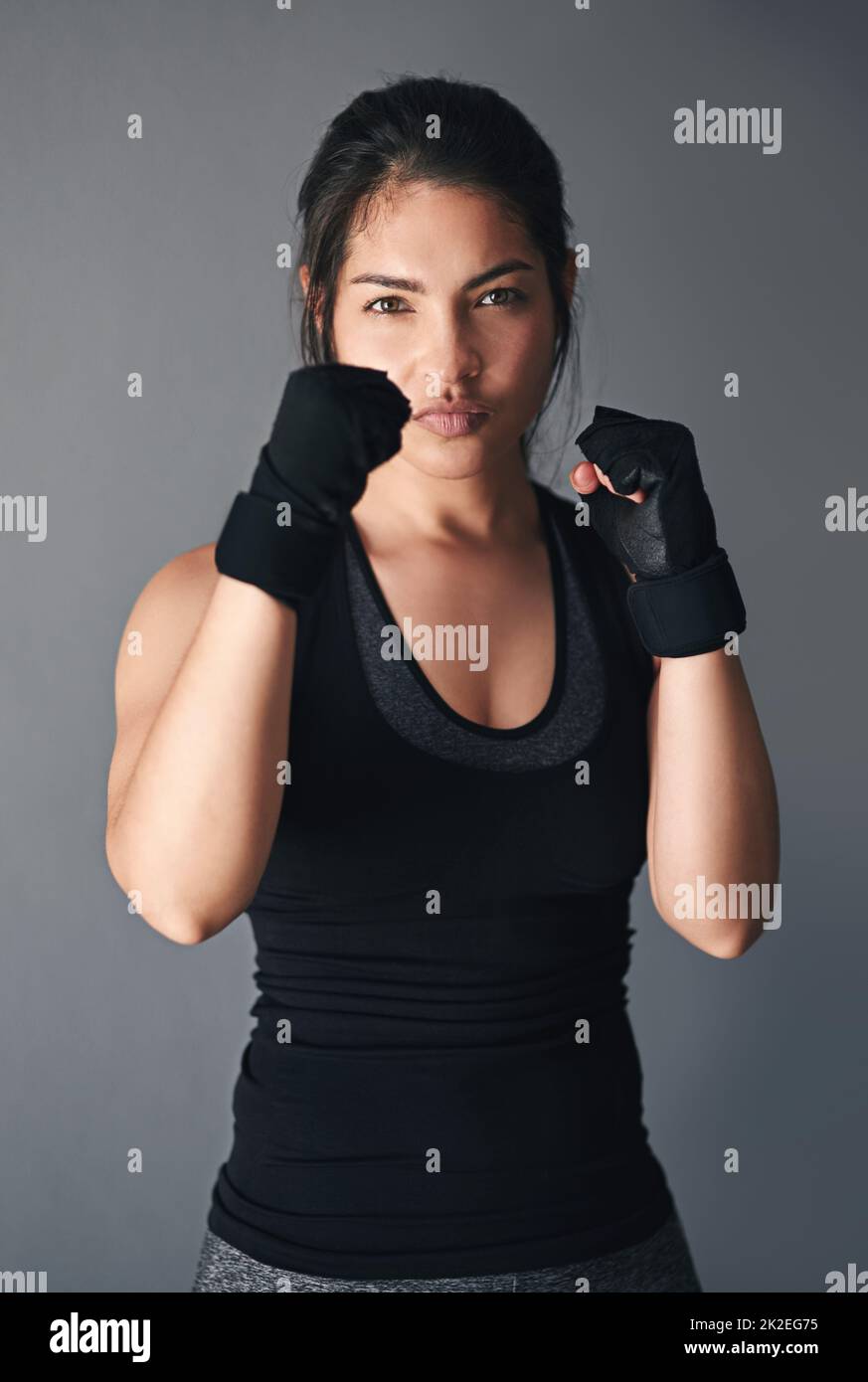 Ready for a fight. Studio shot of a female kickboxer against a gray ...