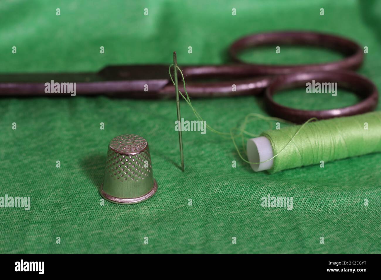 Spool of Green Thread, Thimble and Needle on Green Fabric Stock Photo ...