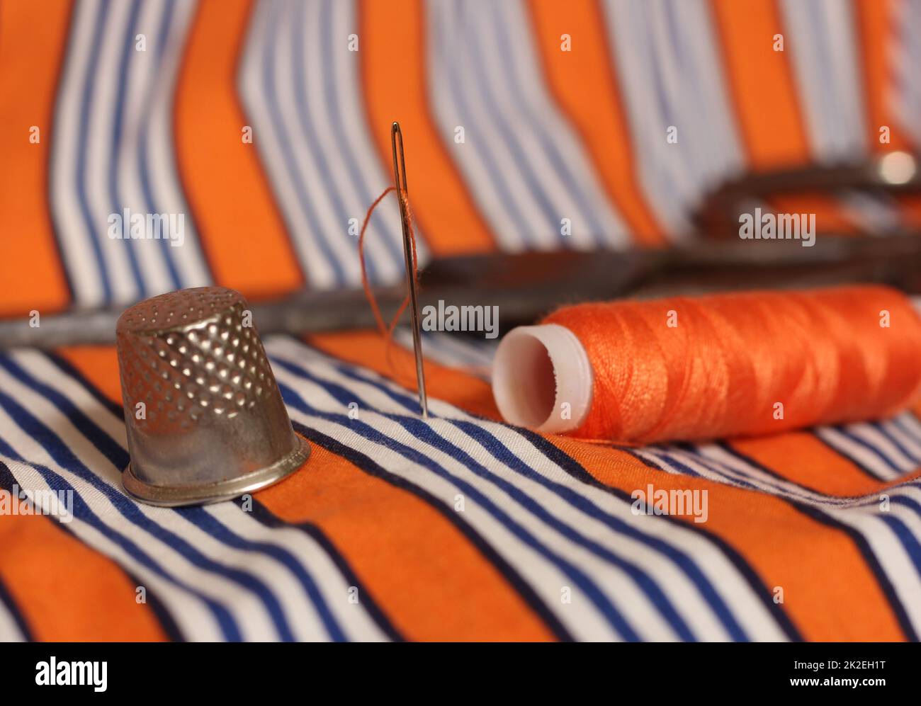 Spool of Orange Thread and Thimble on Orange and White Fabric Stock ...