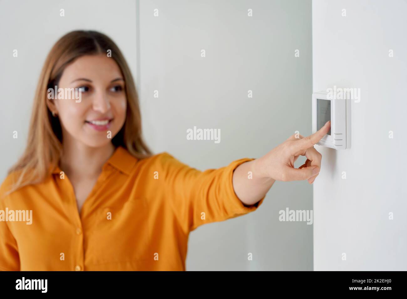 Young woman turns down the temperature for energy saving. Girl ...