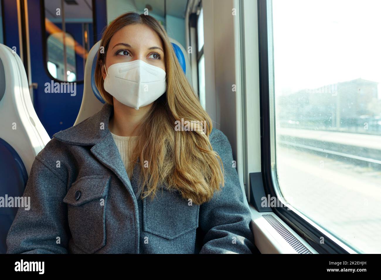 Protective mask mandatory on public transport. Portrait of young woman traveling on train ...