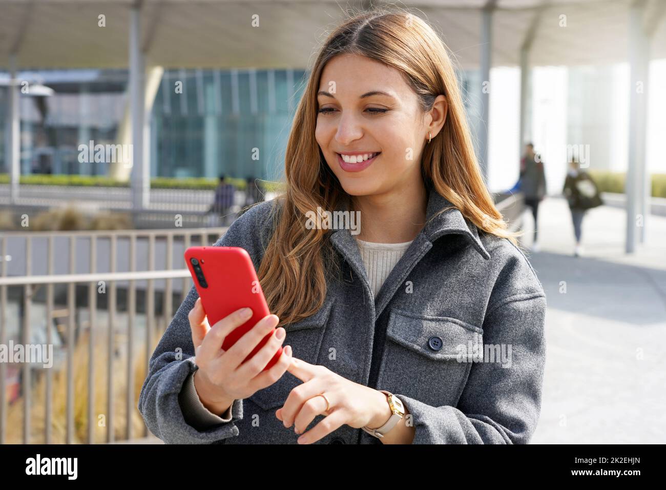 Young woman typing with her finger on her mobile phone outside the ...