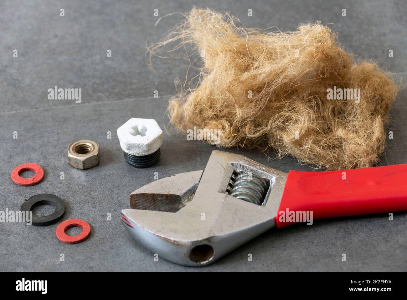 A plumber has a water seal in his hand- On the floor, there is a wrench ...