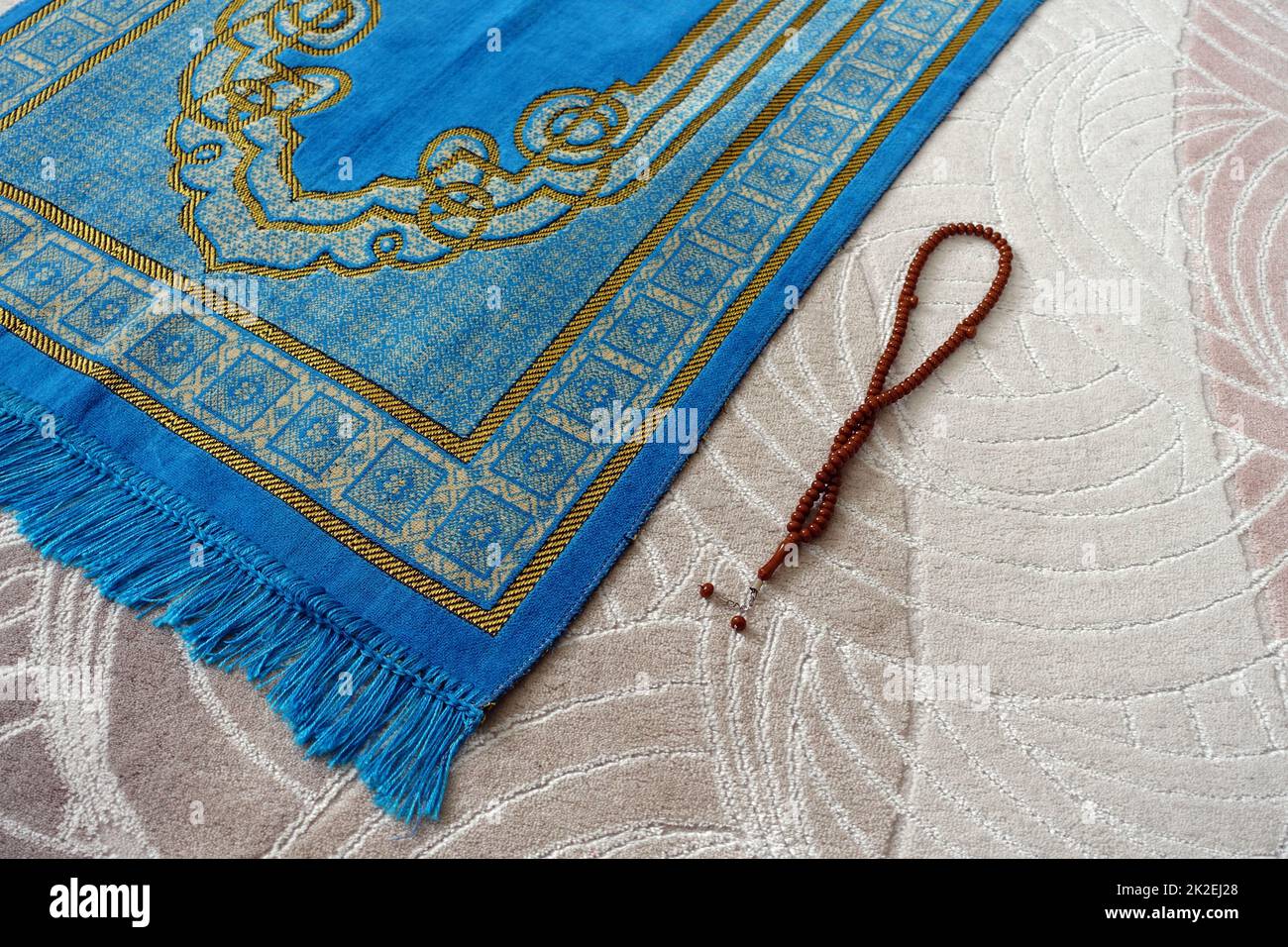 A blue, prayer rug, in the house, of a Muslim, his rosary, next to it ...