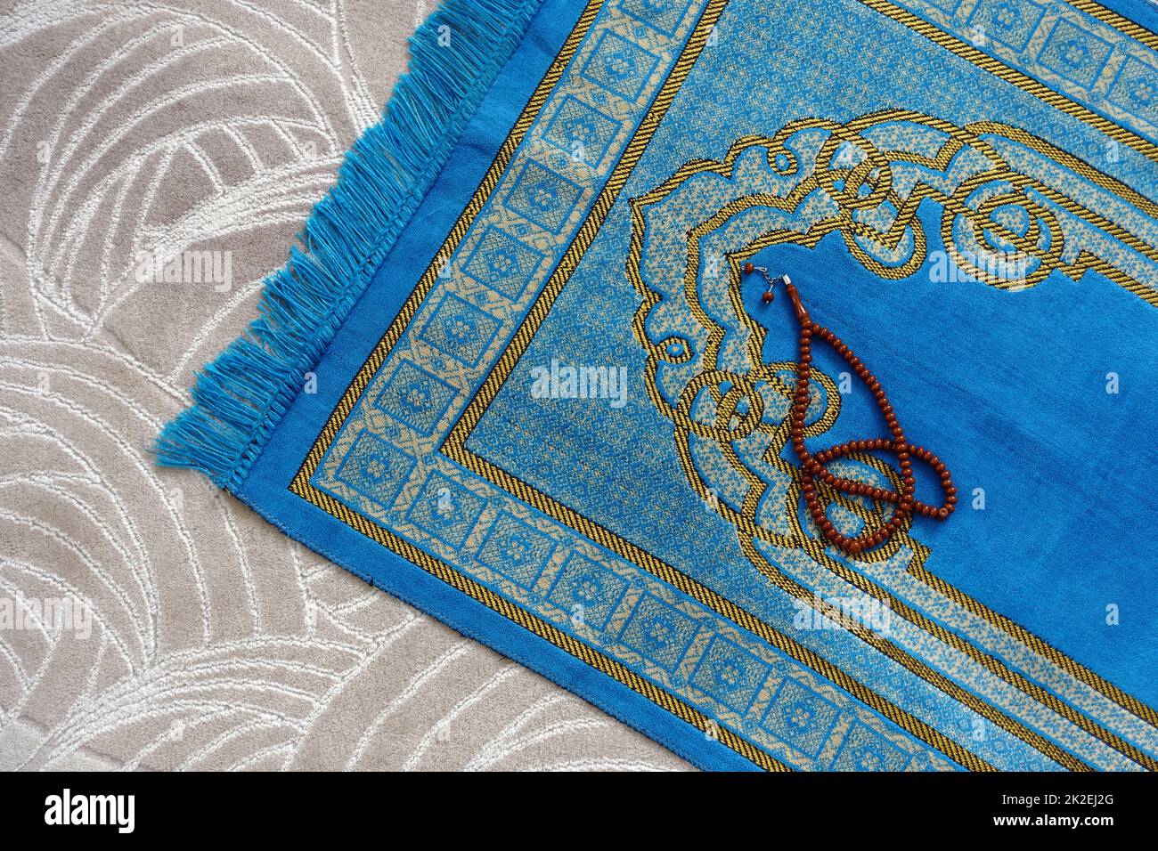 A blue, prayer rug, in the house, of a Muslim, his rosary, next to it ...