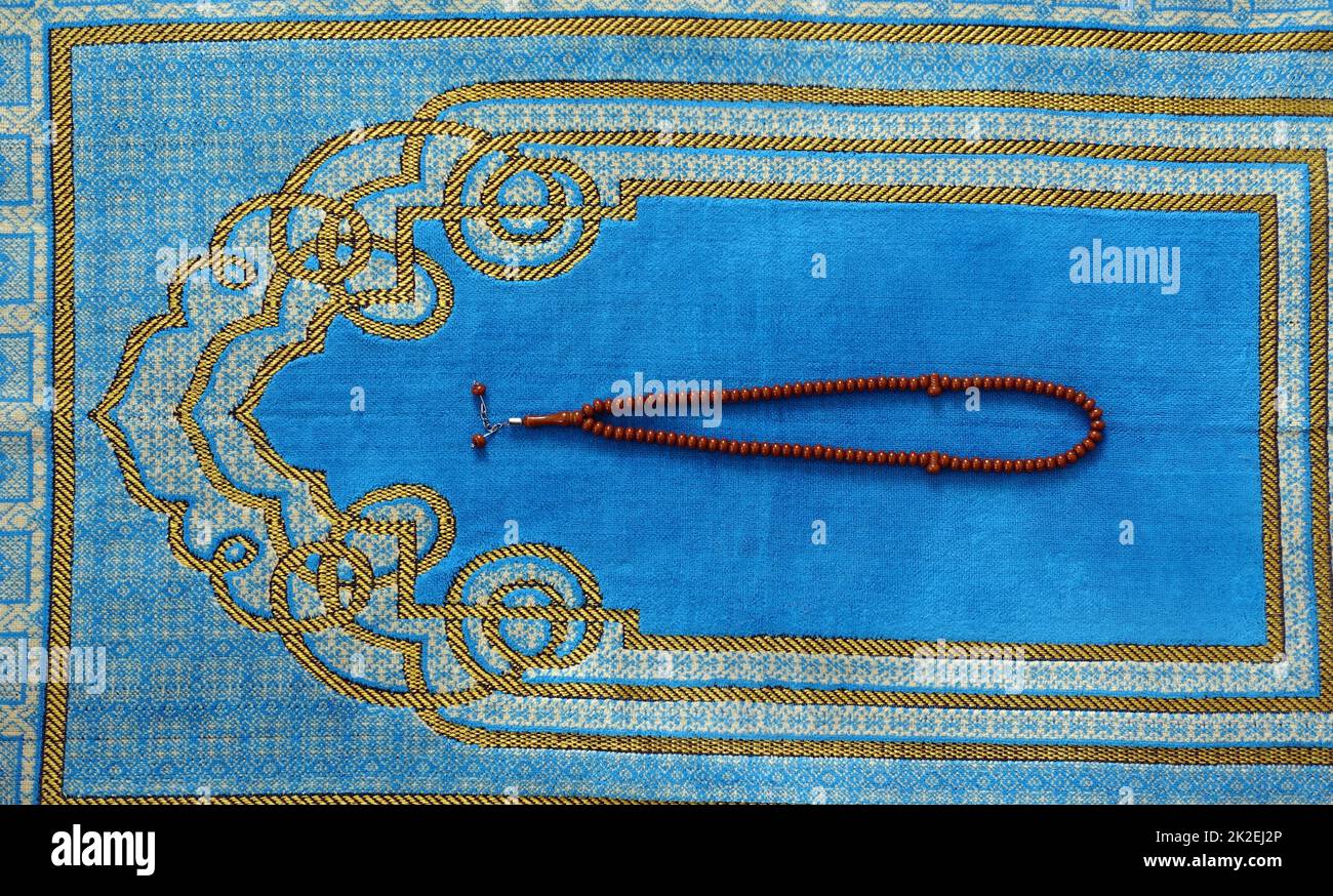 A blue, prayer rug, in the house, of a Muslim, his rosary, next to it ...