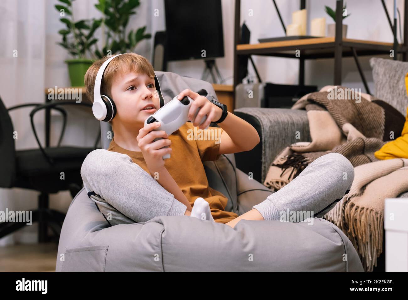 Blond boy teenager with remote control in hand playing video game ...