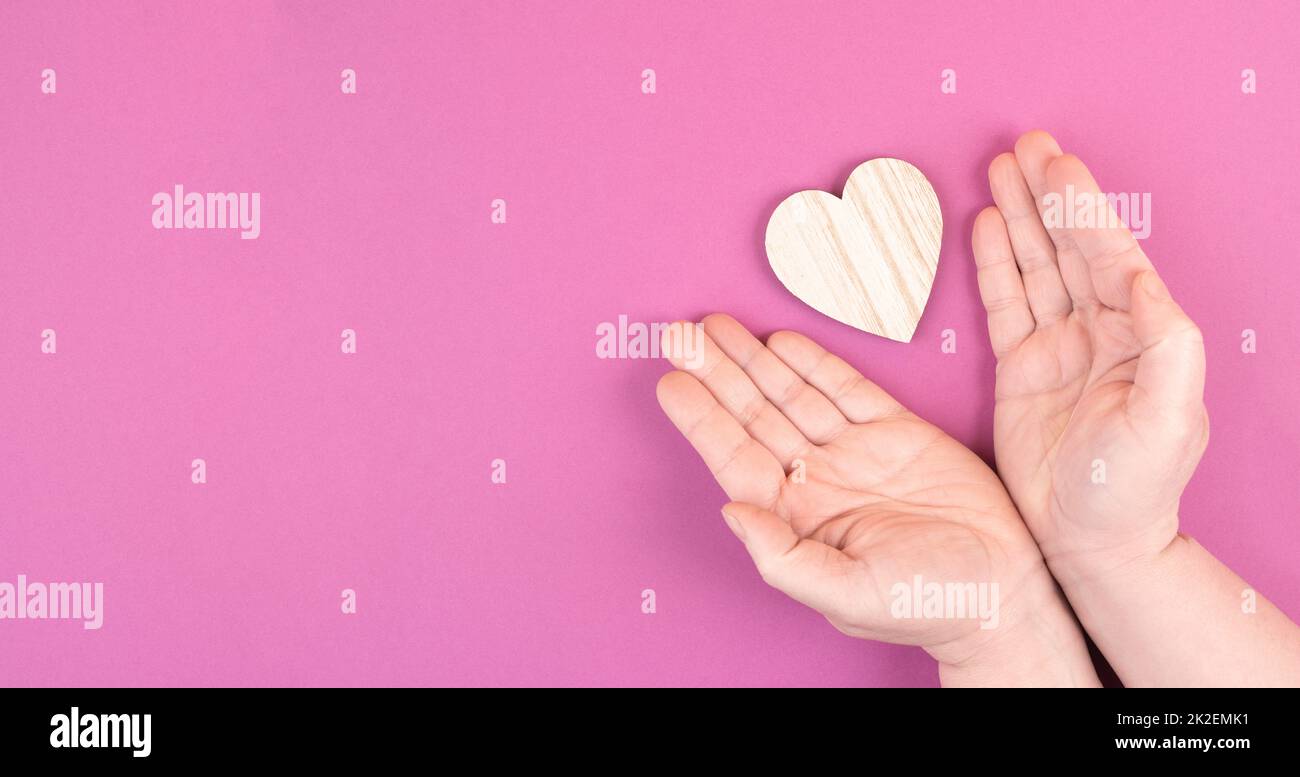 Woman is holding a pink heart in her hand, blue colored background ...